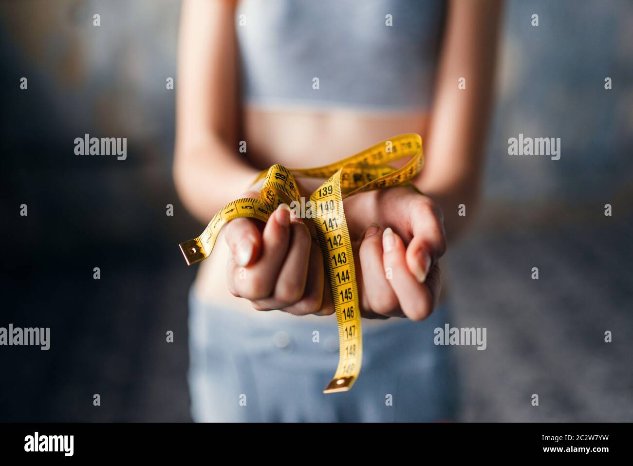 Skinny female hands are tied with measuring tape. Fat or calories ...