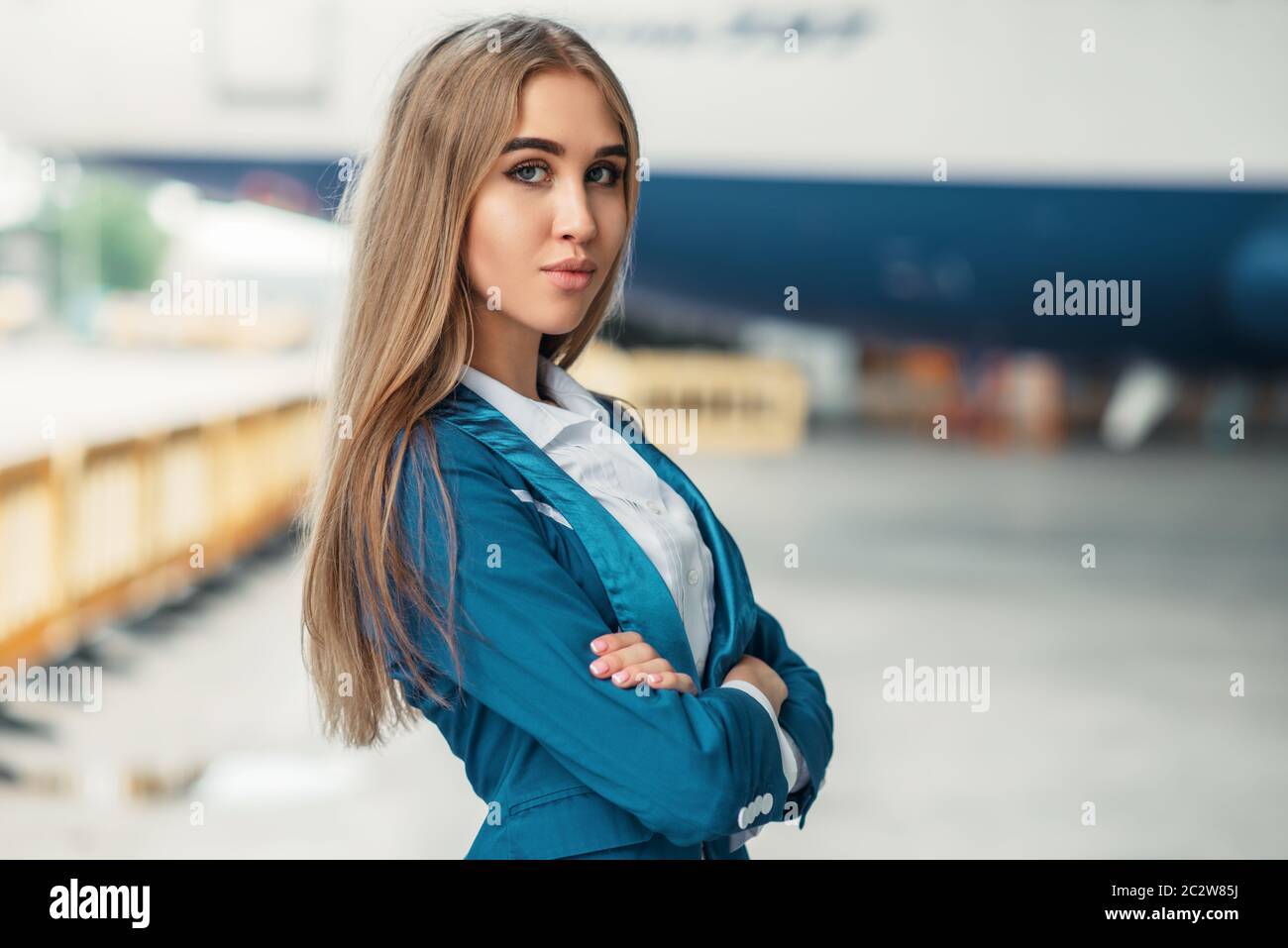 Attractive stewardess in uniform poses against airport building. Air ...