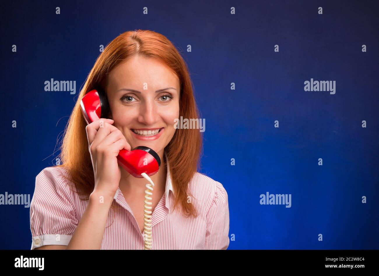 Redhead smiling girl with retro red telephone Stock Photo - Alamy