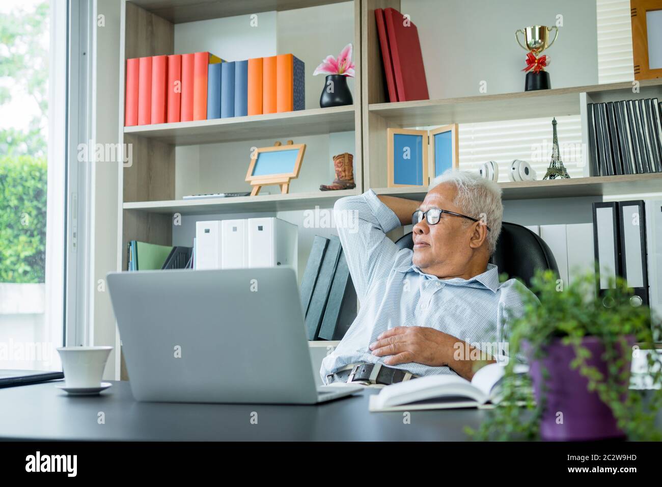 Asian elderly man sitting in front of a laptop computer, He is sitting ...