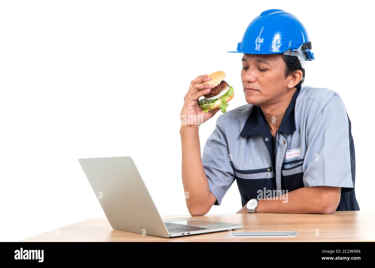 Asian man worker smiling and holding a hamburger in the living room ...