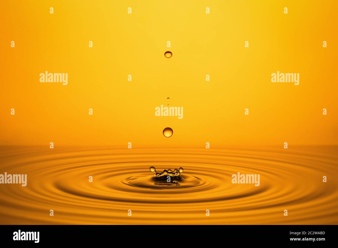 Ripple of the golden surface of yellow liquid with drops Stock Photo ...