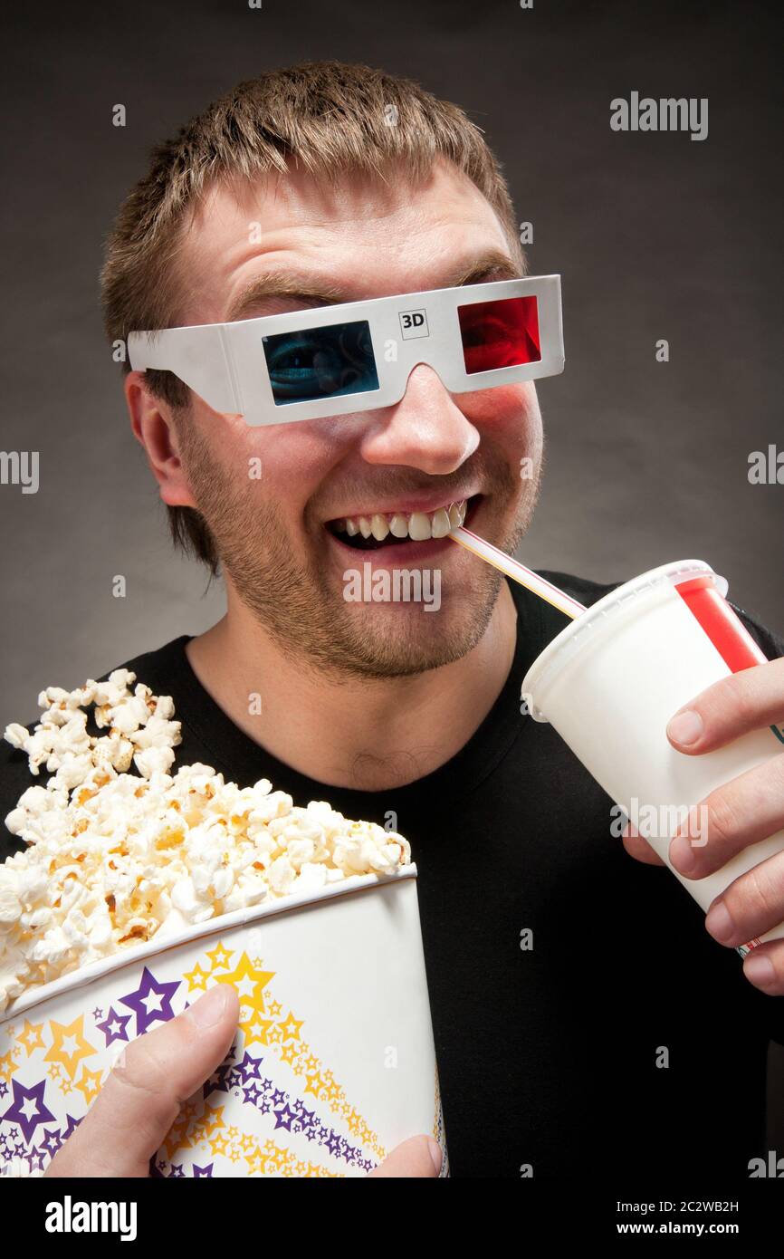 Funny man watching 3D movie, drinking soda and eating popcorn Stock Photo - Alamy