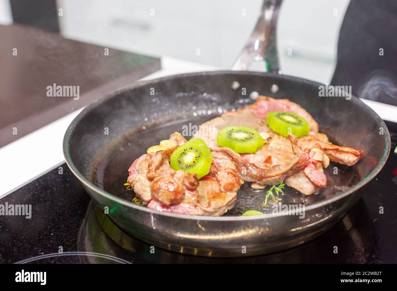 Meat with kiwi fruit on the frying pan Stock Photo - Alamy