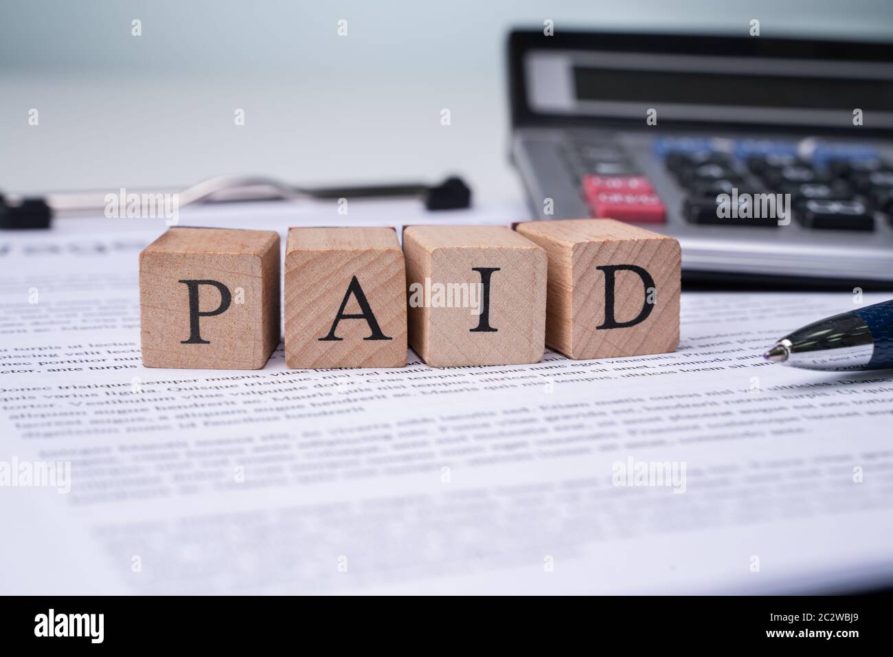 Close-up Of Paid Text On Wooden Blocks Over Office Documents With ...