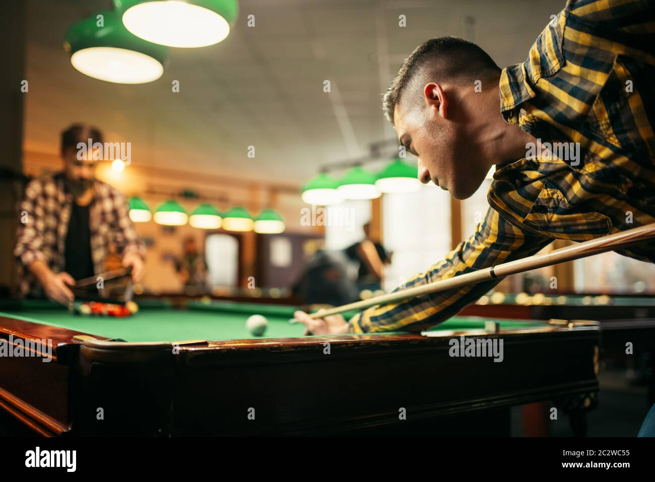 Two male billiard players with cue at the table with colorful balls ...