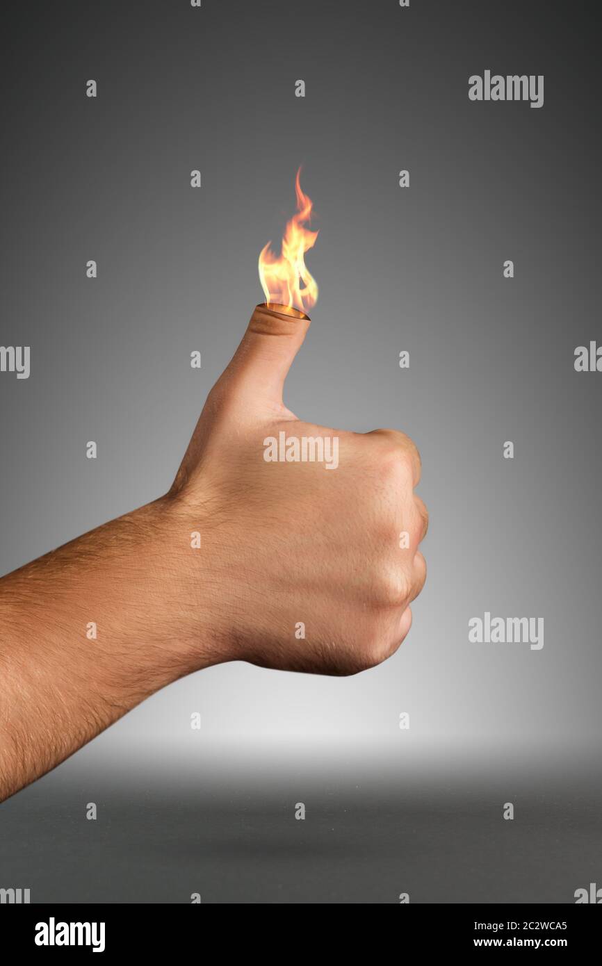 Burning thumb up over grey background Stock Photo - Alamy