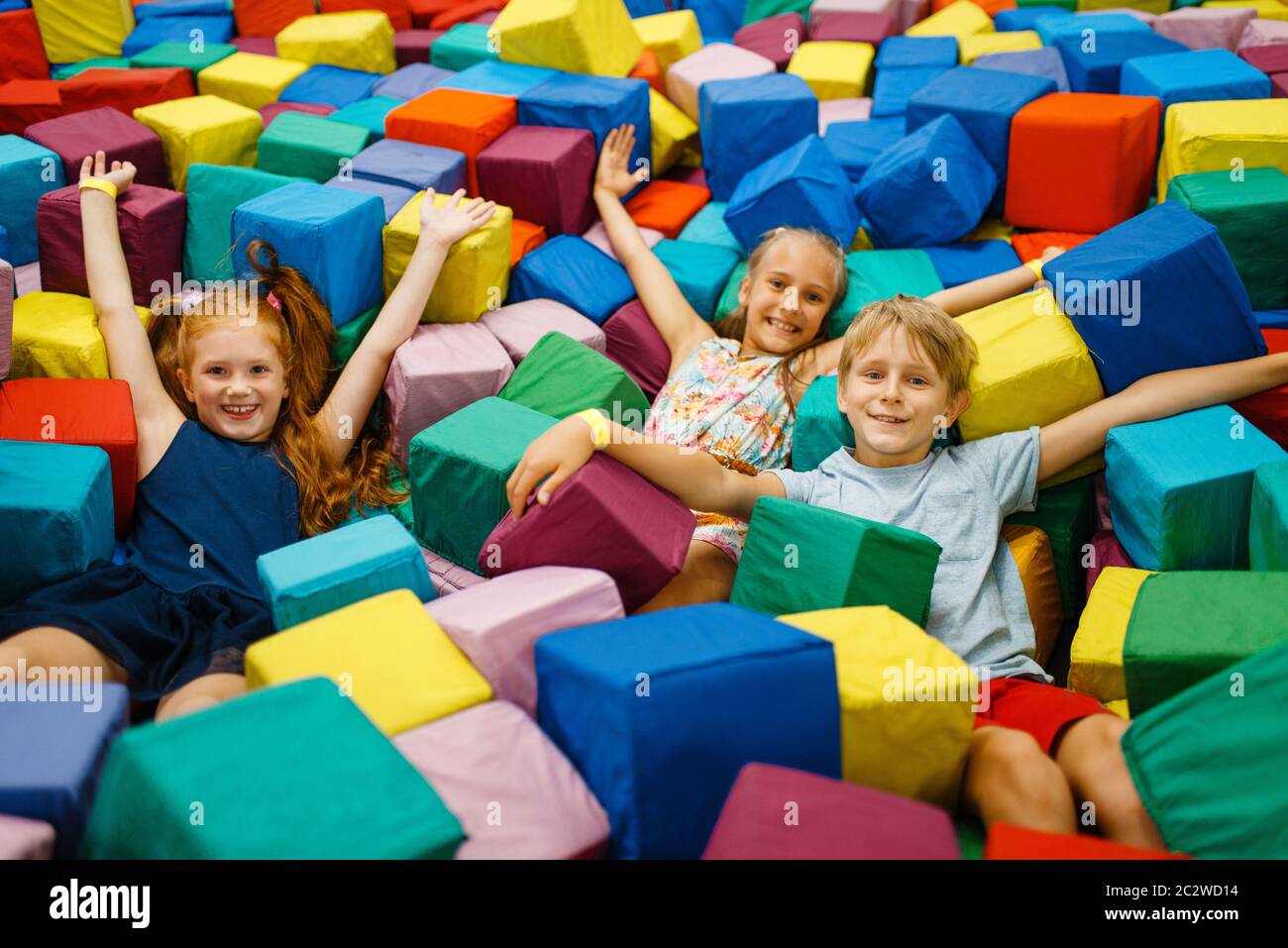 Happy children lying in soft cubes, playground in entertainment center ...
