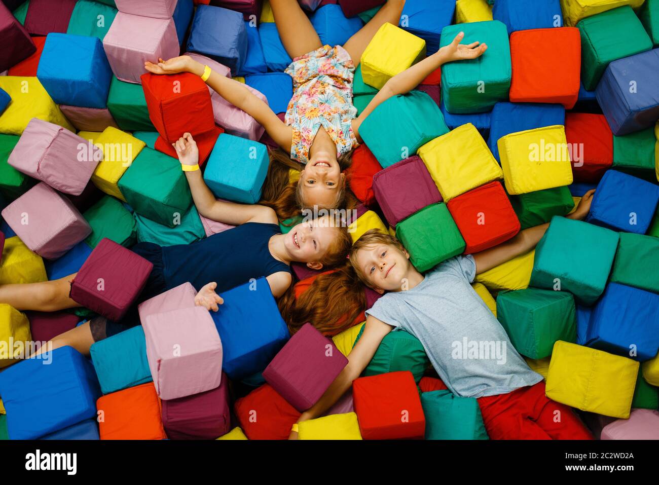 Happy children lying in soft cubes, playground in entertainment center ...