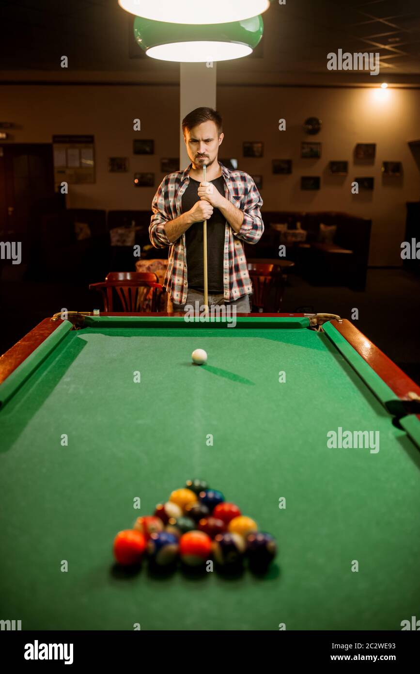 Male billiard player with cue at the table with colorful balls. Man ...