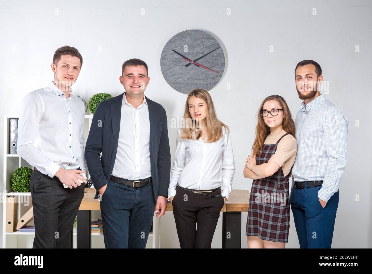 Smiling employees standing looking camera making team picture in office ...