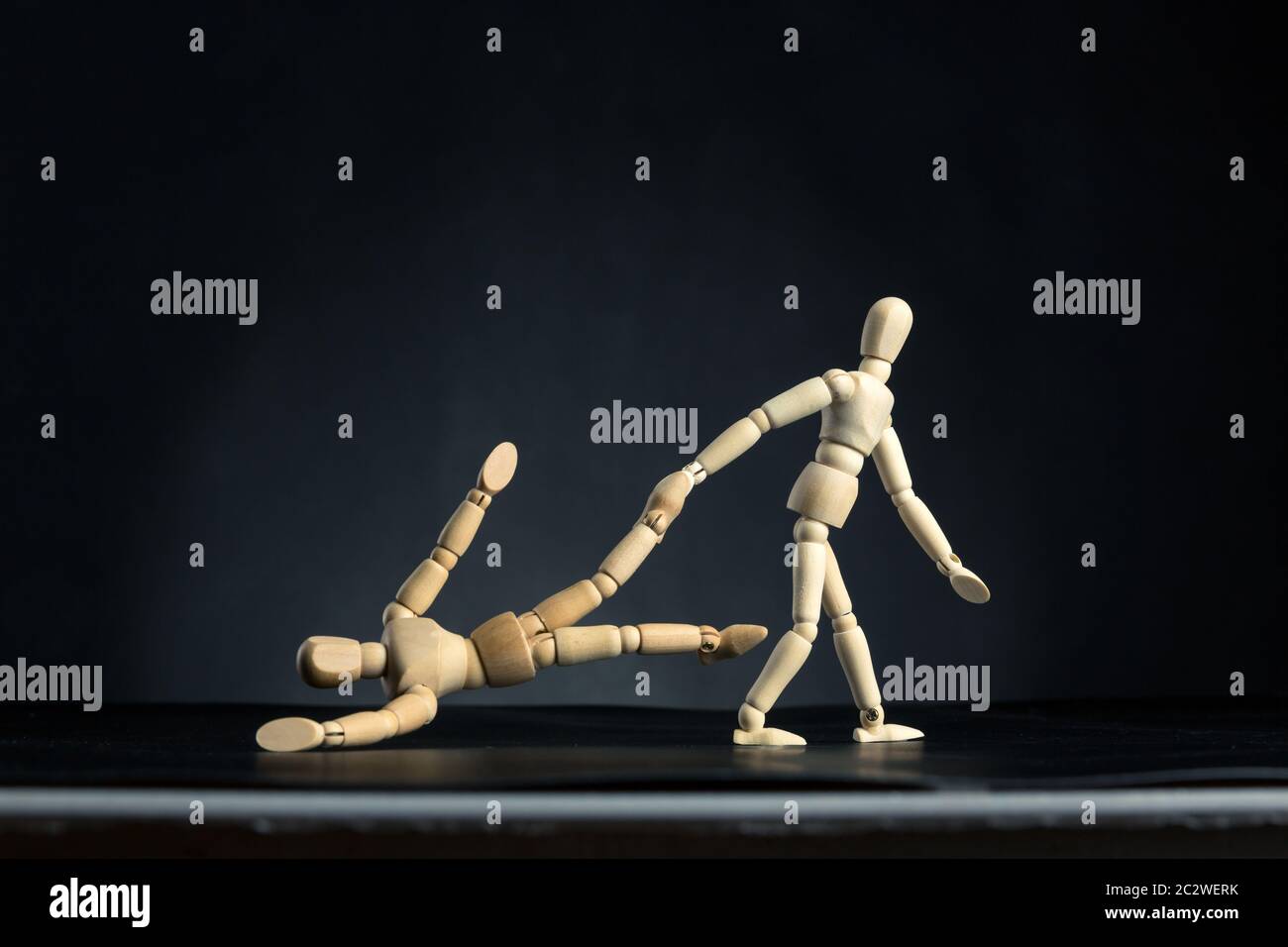 Wooden carved figures, man pulling woman by leg over black Stock Photo ...