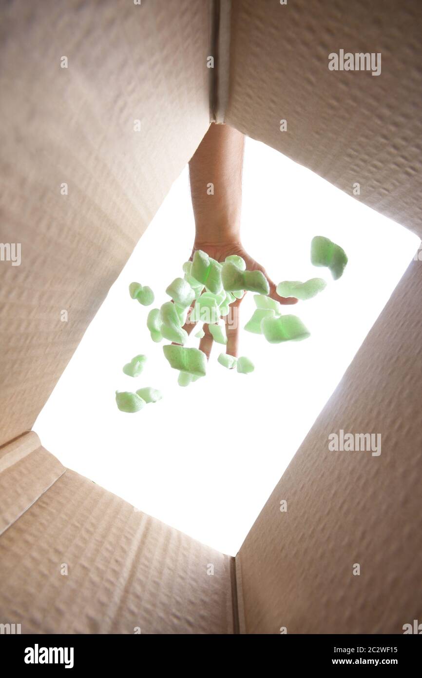 Hand throwing packing polyfoam into cardboard box Stock Photo - Alamy