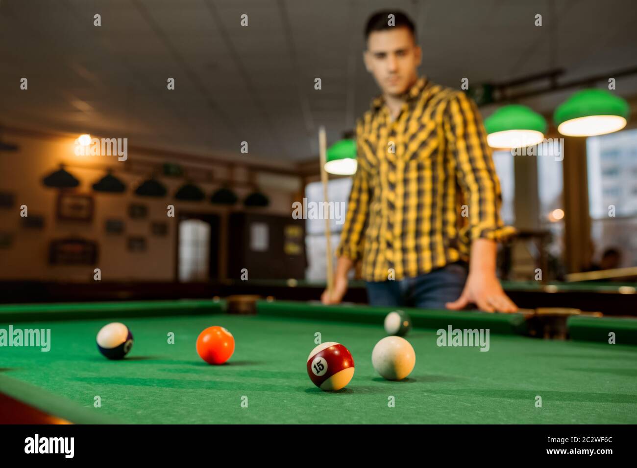 Male billiard player with cue, view from the table with colorful balls ...