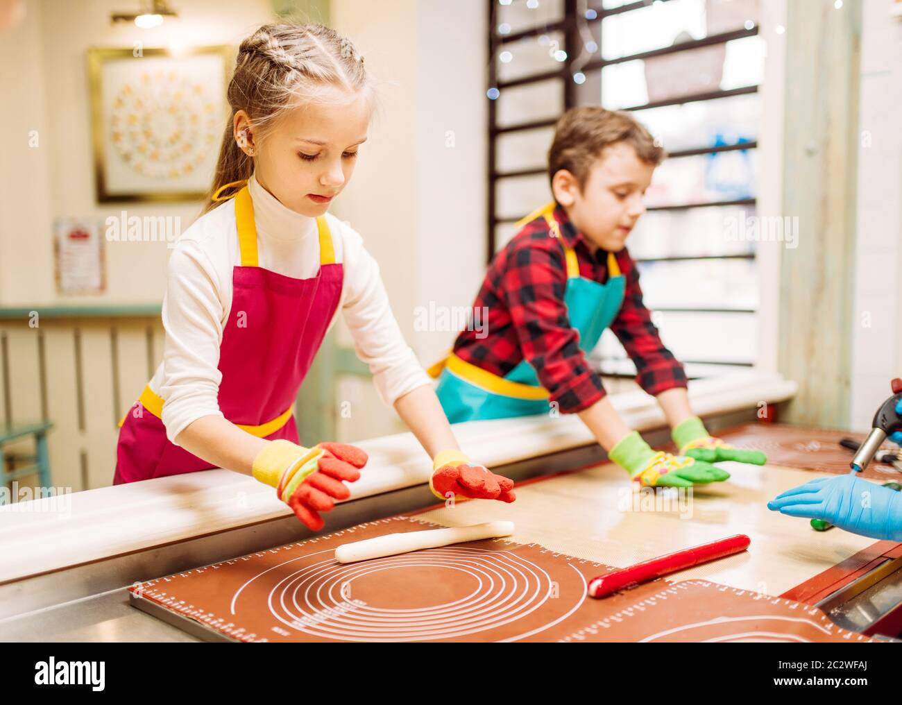 Little girl and boy in workshop at pastry shop learn to make caramel ...