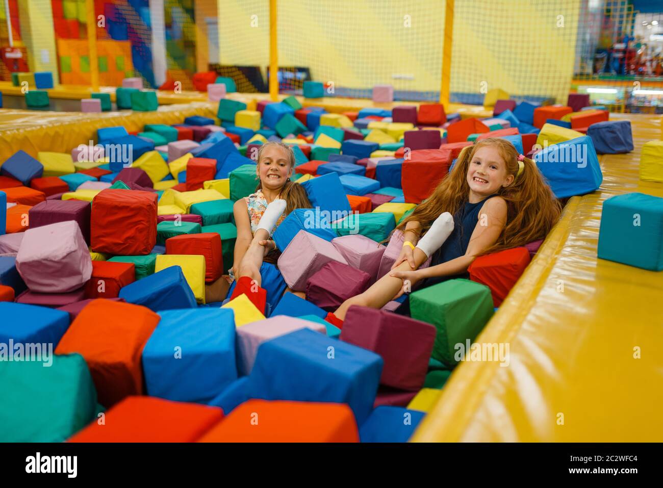 Two little girls lying in soft cubes, playground in entertainment ...