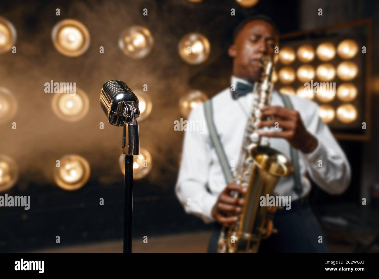 Male jazz performer plays the saxophone on the stage with spotlights ...