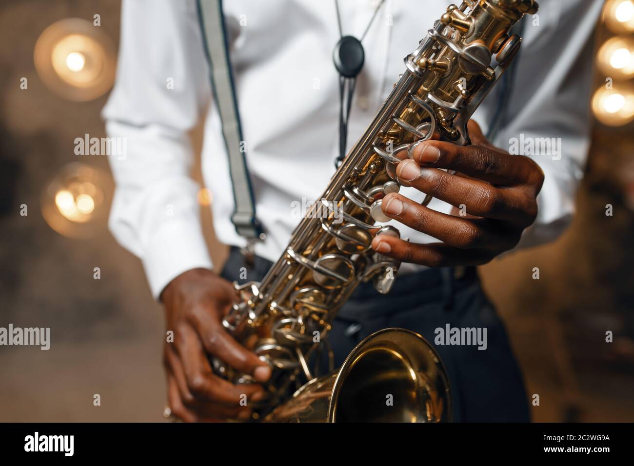 Male jazz performer plays the saxophone on the stage with spotlights ...