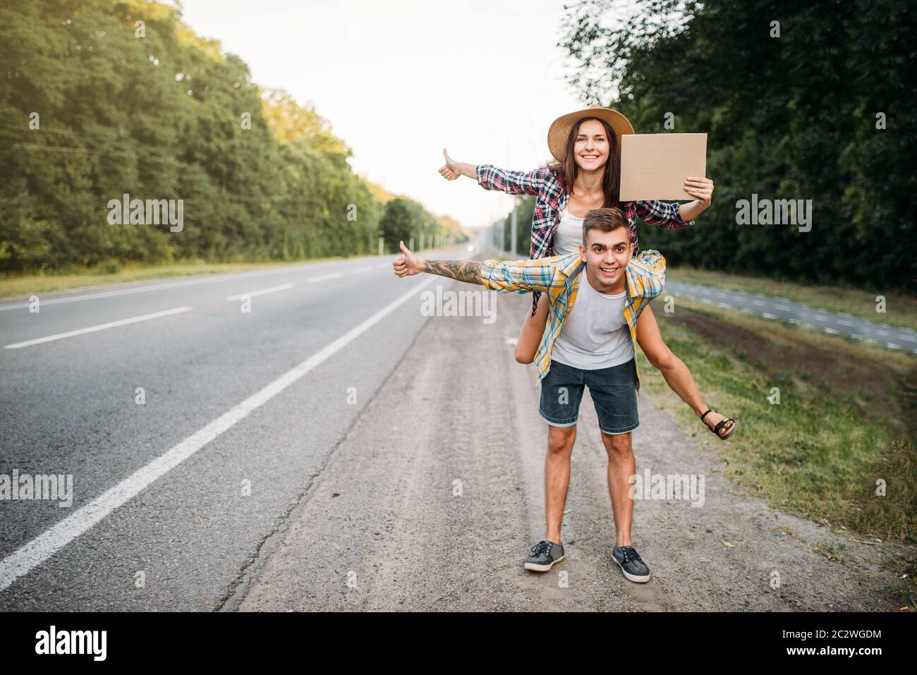Young hitchhiking couple with empty cardboard. Hitchhike adventure of ...