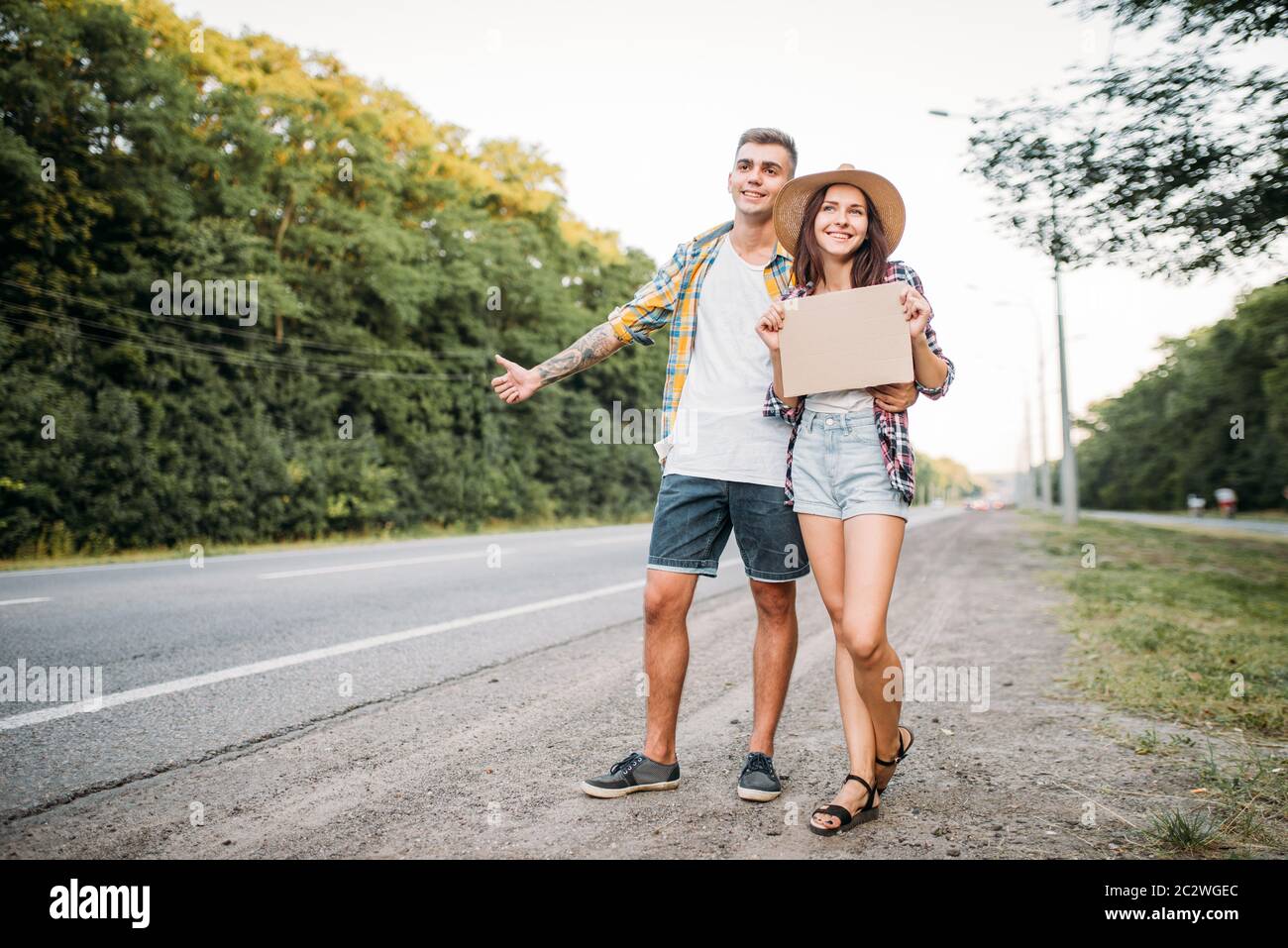 Young hitchhiking couple with empty cardboard. Hitchhike adventure of ...