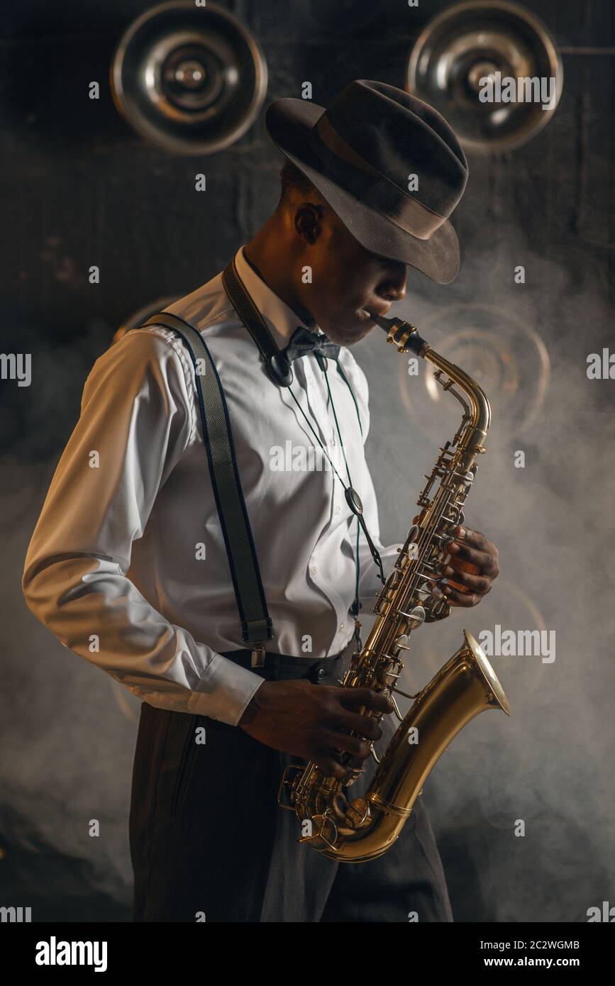 Black jazzman plays the saxophone on the stage with spotlights. Black ...
