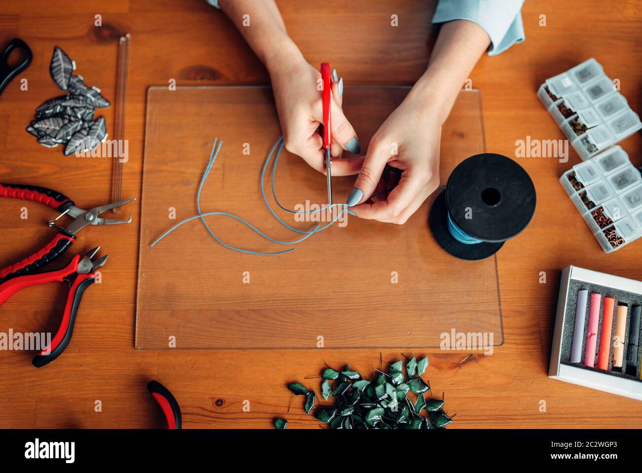 Female person hands with pliers, top view. Handmade jewelry. Needlework ...