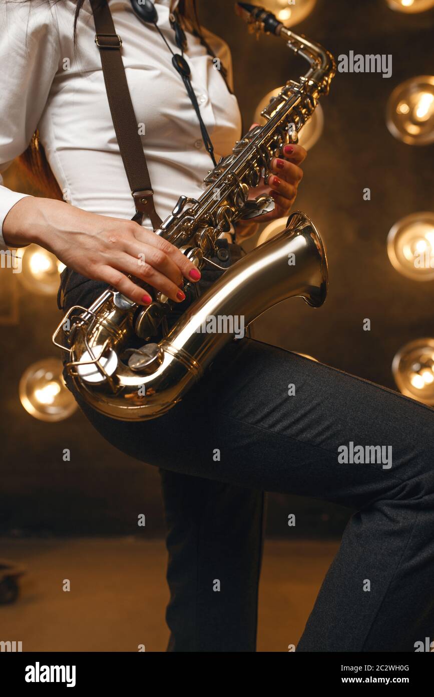 Female saxophonist plays the saxophone on the stage with spotlights ...