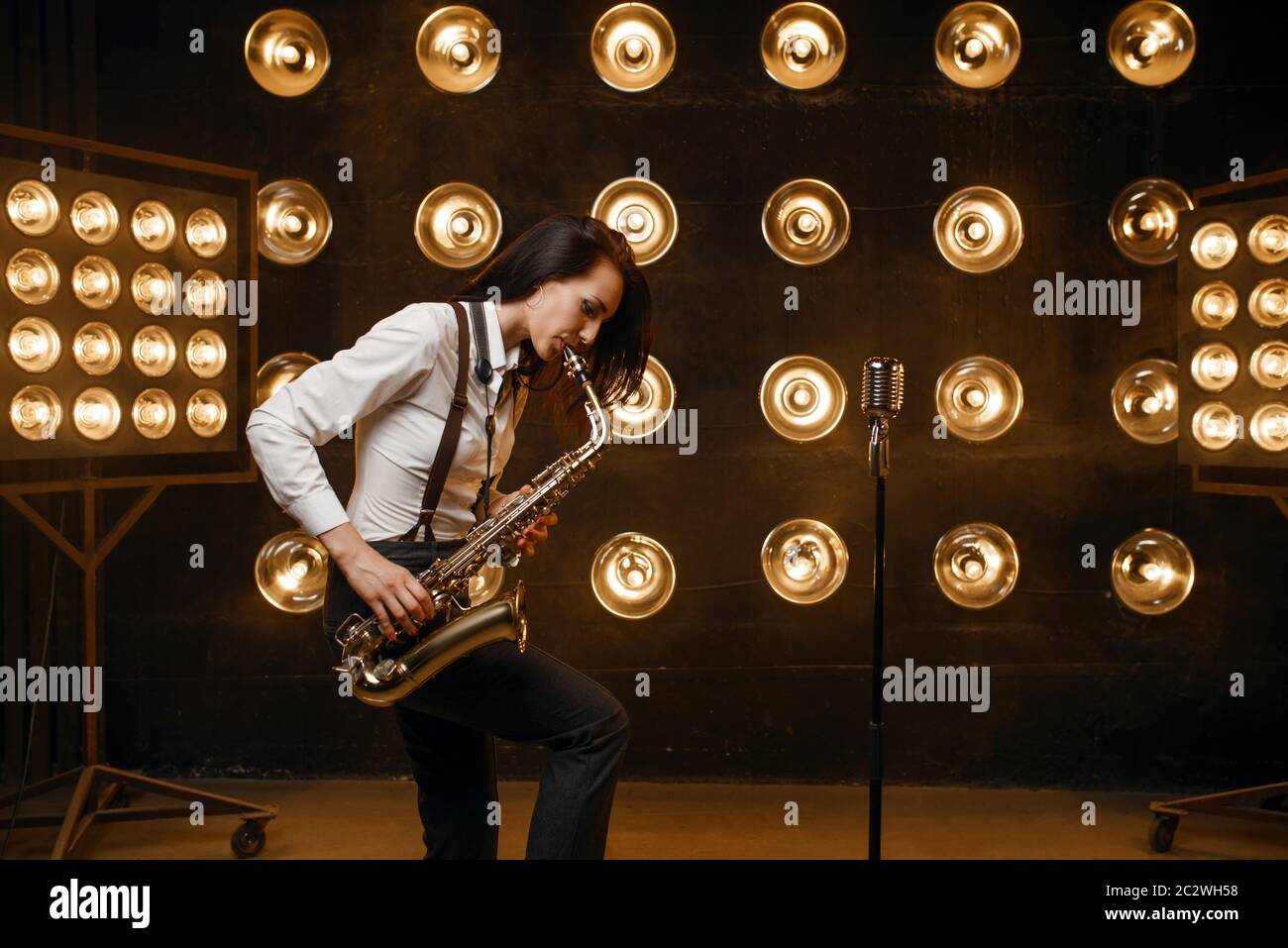 Female saxophonist plays the saxophone on the stage with spotlights ...