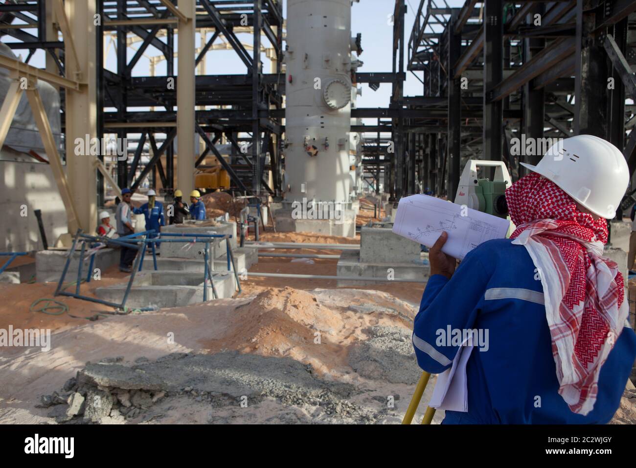A surveyor working for an oil and gas company using a theodolite in the ...