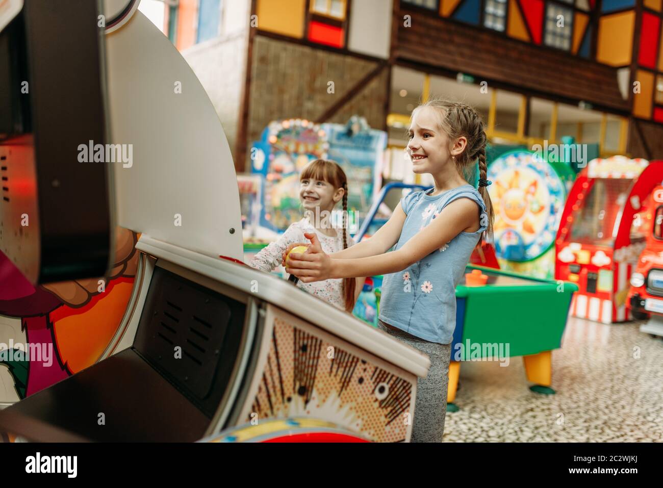 Two little girls plays on video game machine, children entertainment ...