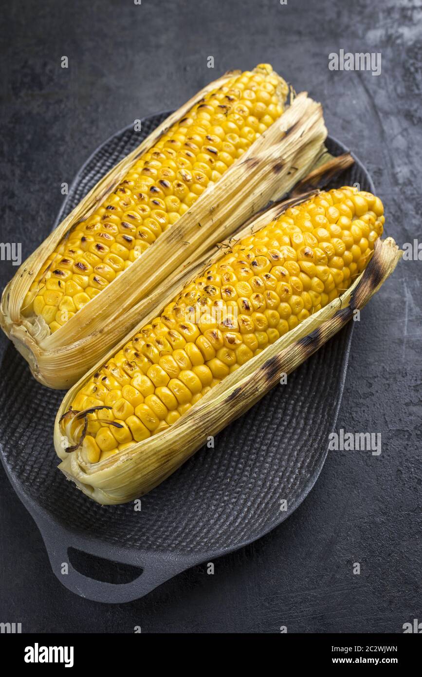 Traditional barbecue corn green as closeup on a cast iron design plate ...