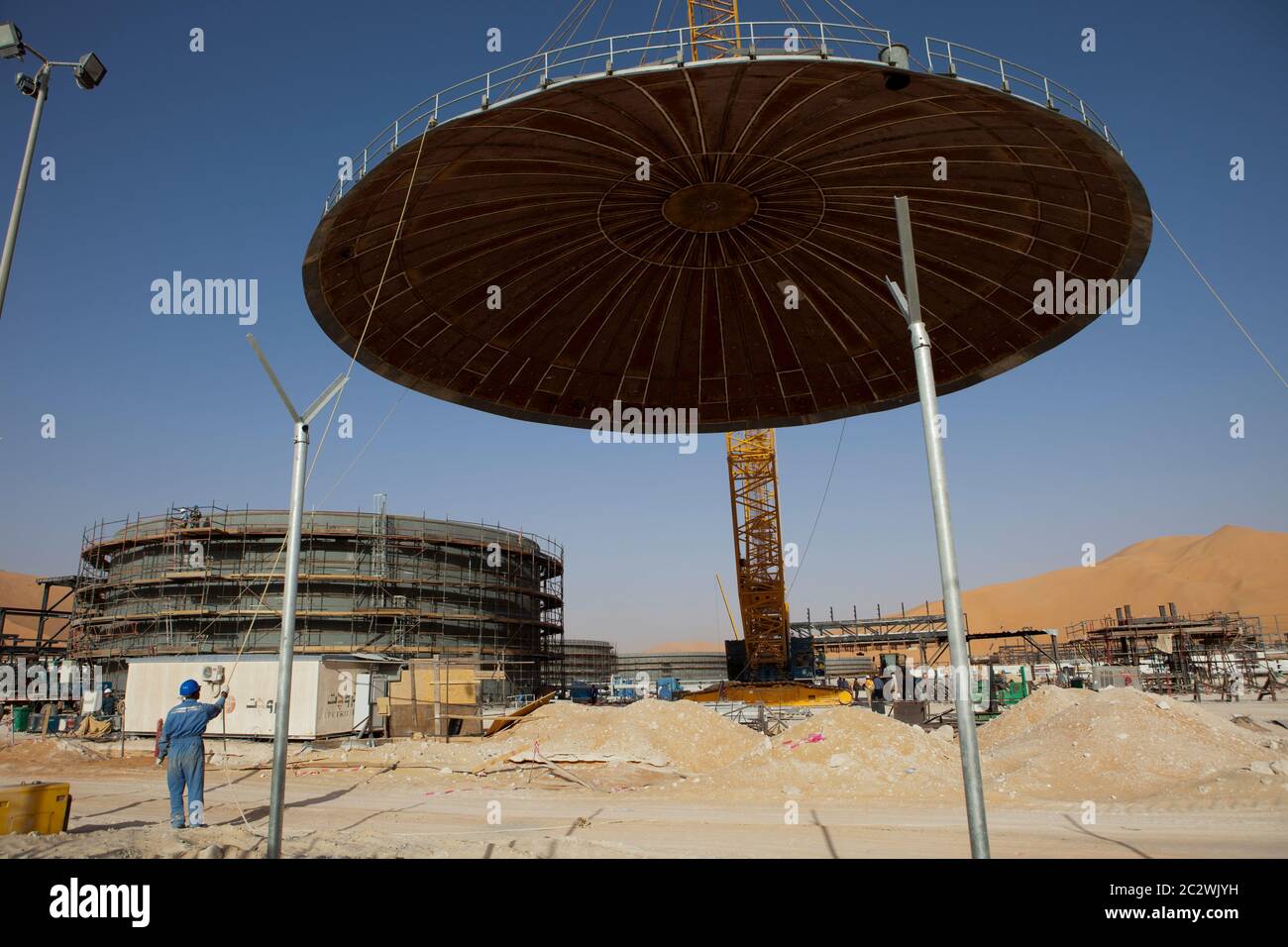 A crew member holds a rope to control contol the heavy lift of a large ...
