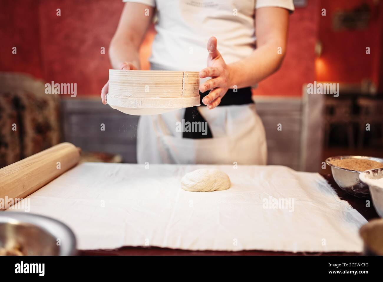 Male person works with dough on wooden kitchen table. Homemade strudel ...