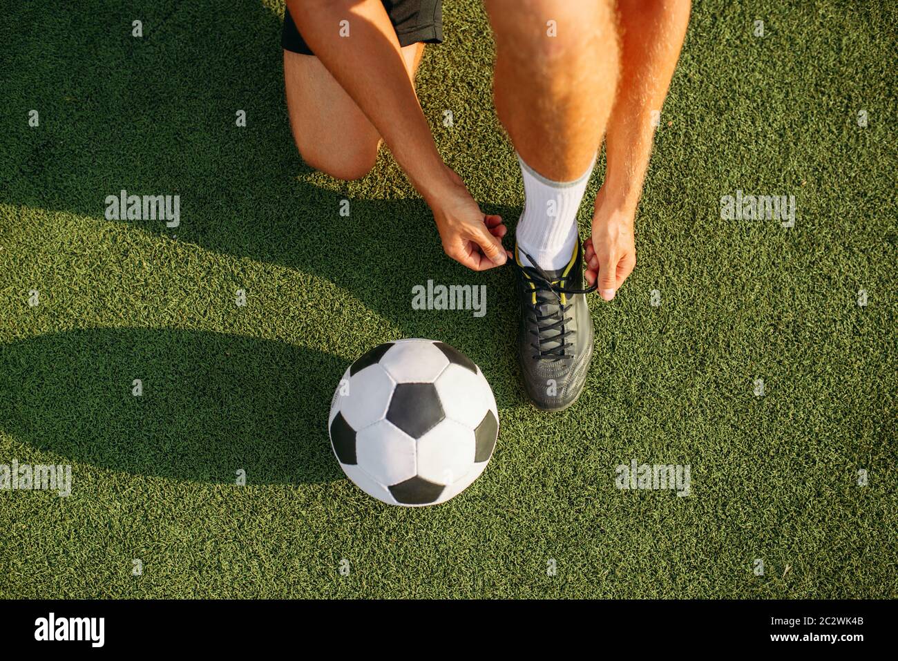 Male soccer player ties his shoelaces on boots, top view. Footballer on ...