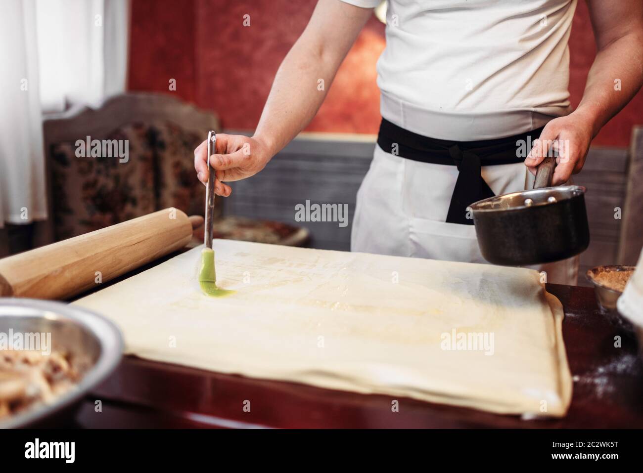 Male chef in white apron cooking apple strudel on the kitchen. Homemade ...