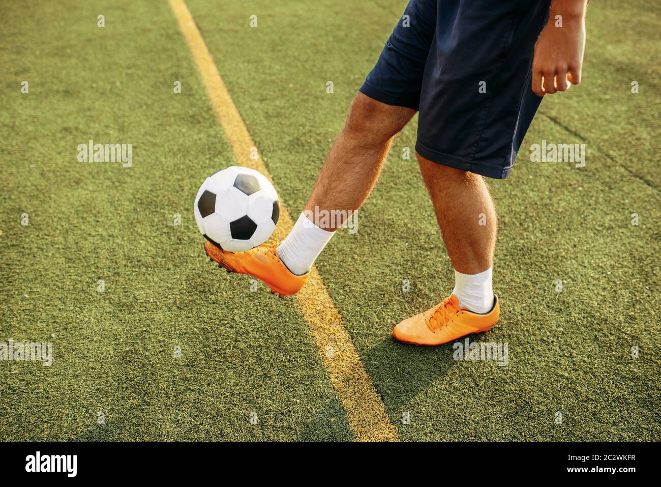 Male soccer player with ball standing on line on the field. Footballer ...