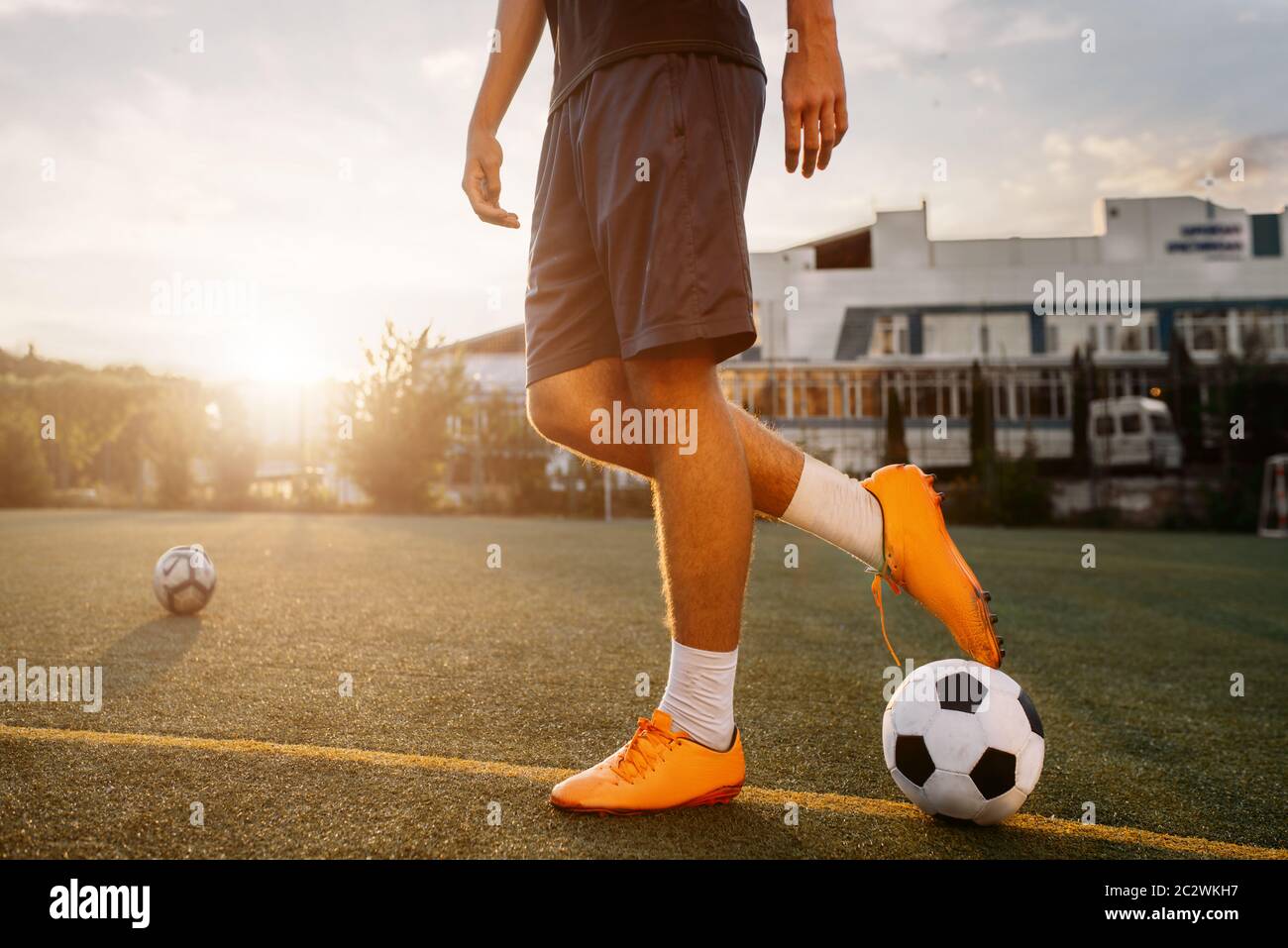 Soccer player with ball on the field at sunrise. Footballer on outdoor ...
