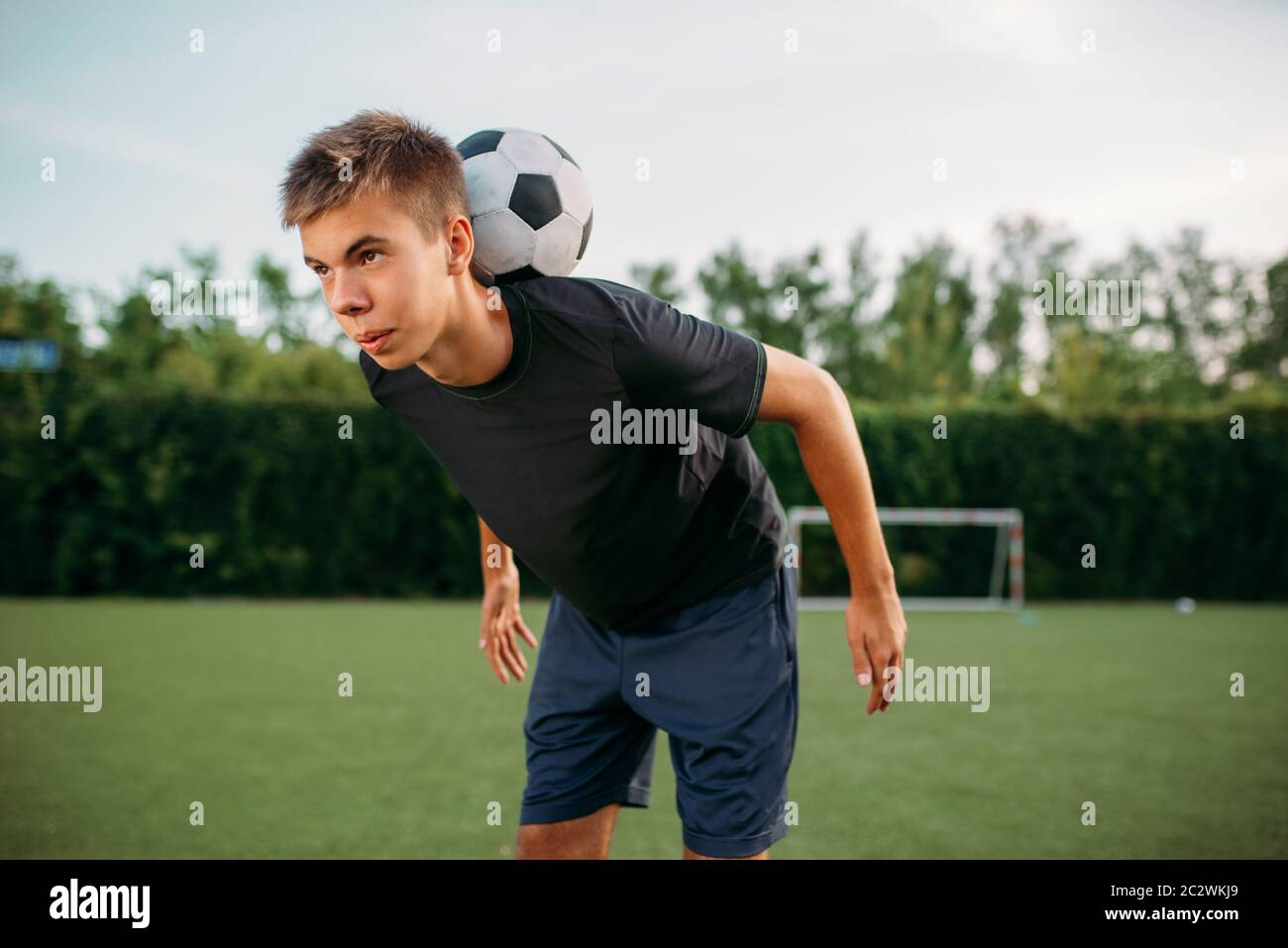 Male soccer player keeps balance with the ball on his neck on the field ...