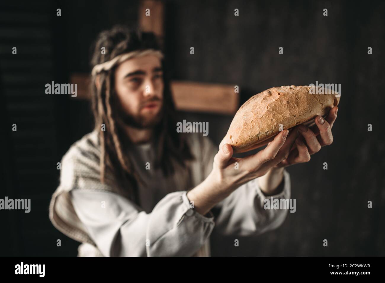 Jesus Christ with bread in hands, sacred food, crucifixion cross on ...