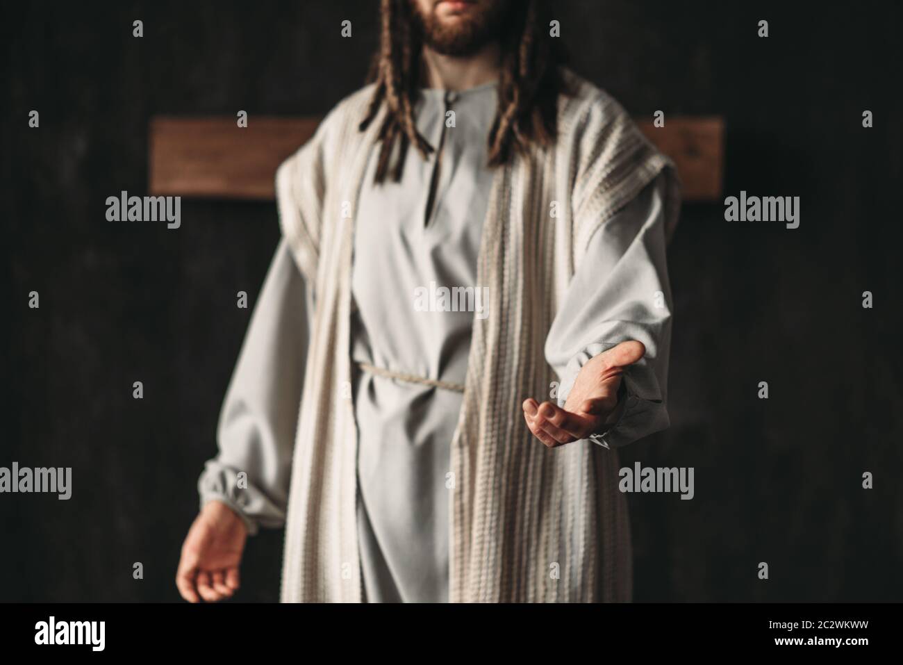 Man in the image of Christ reaching out his hand, dark background ...
