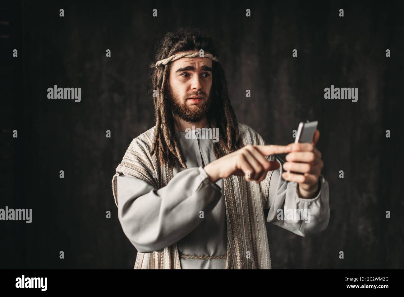 Man in the image of Jesus Christ holds mobile phone, dark background ...