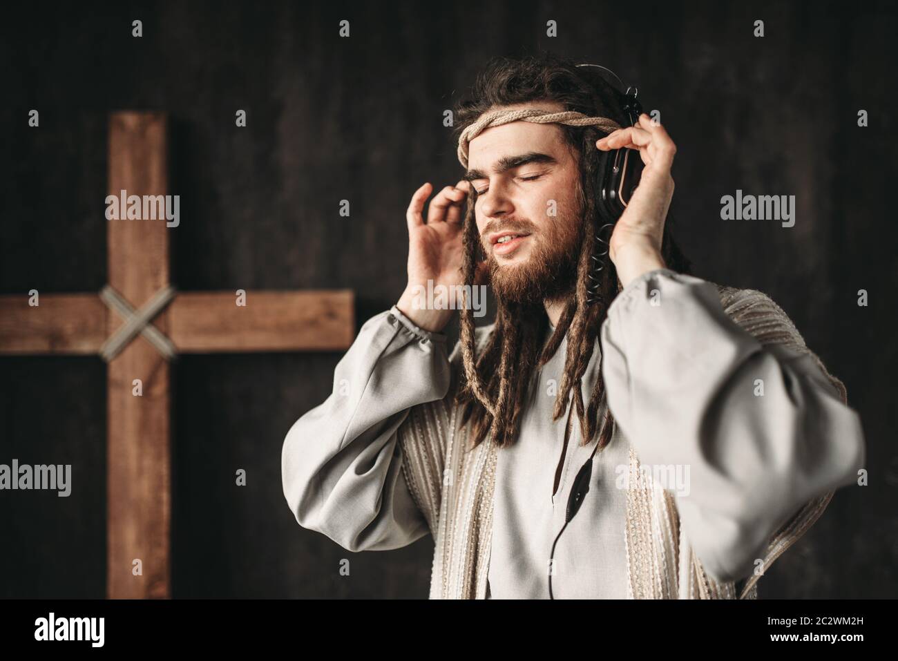 Man in the image of Jesus Christ listening to music with headphones ...