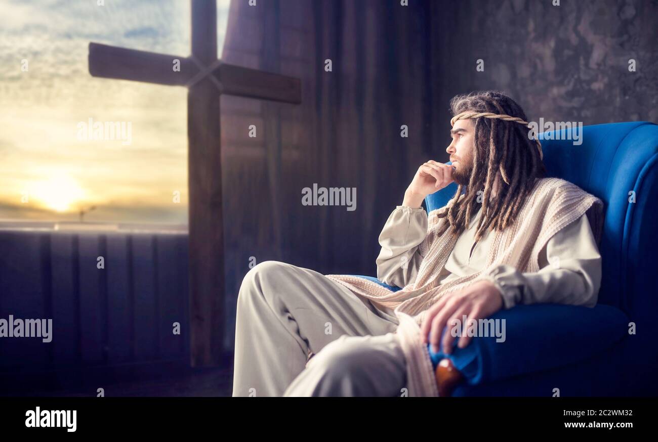 Thoughtful man in the image of Jesus Christ sitting in a chair against ...