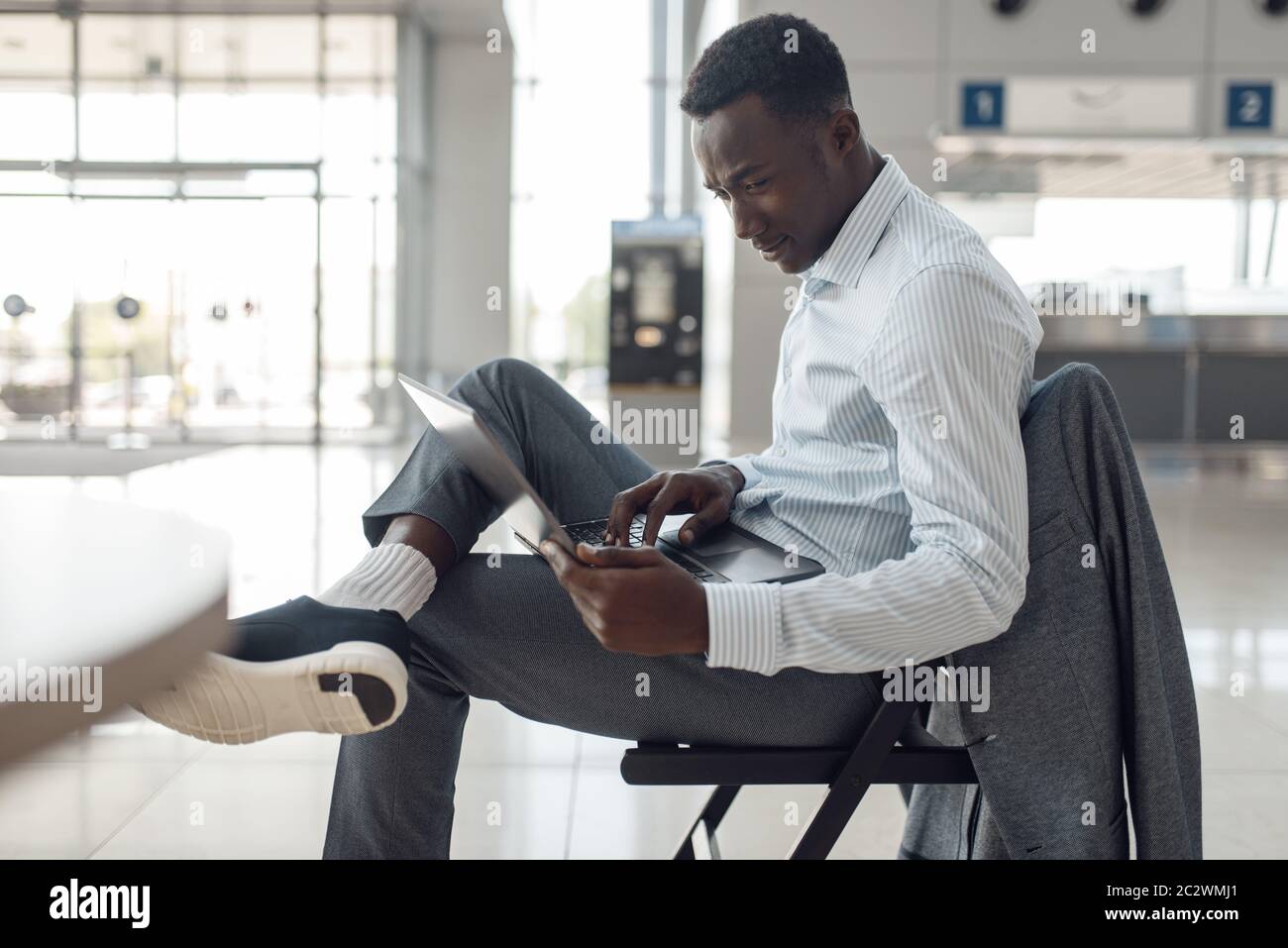 Young black businessman using laptop in car showroom. Successful ...