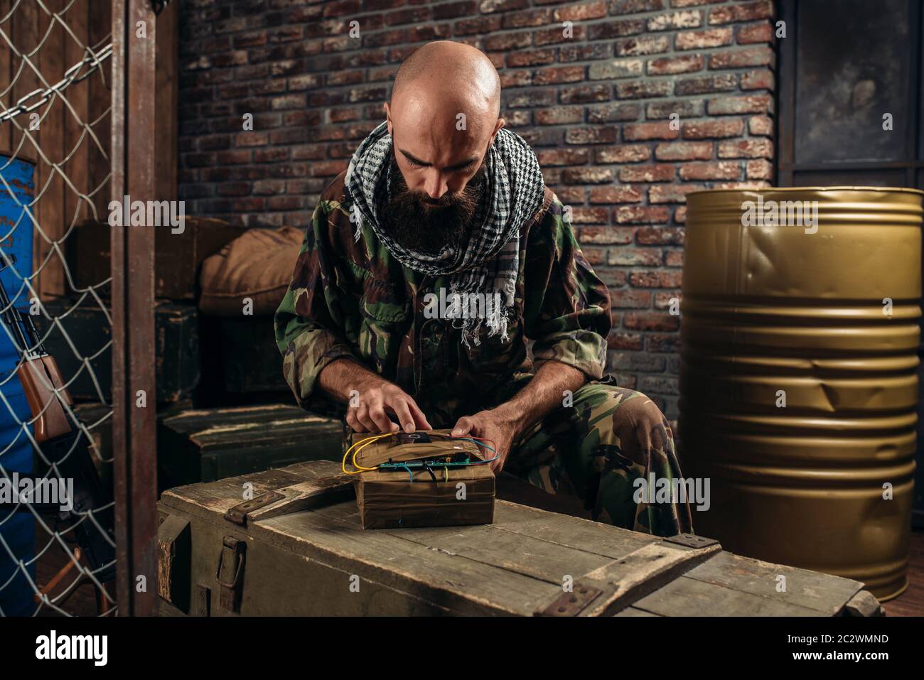 Bearded terrorist in uniform sets the bomb on the barrels of fuel or ...