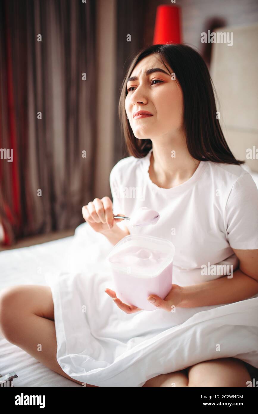 Crying woman sitting in bed and eats ice cream, female depression ...