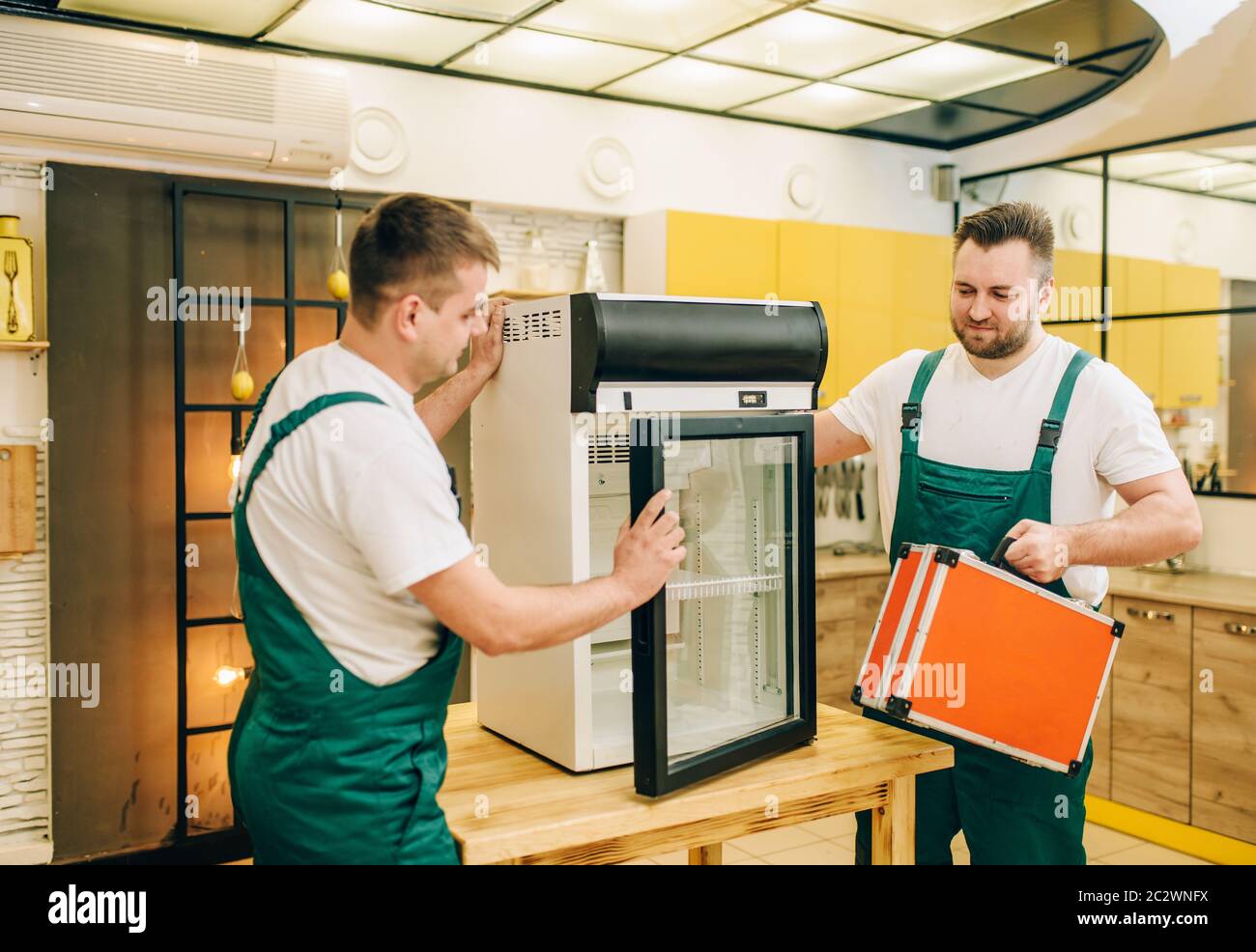 Male workers in uniform repair refrigerator at home. Repairing of ...