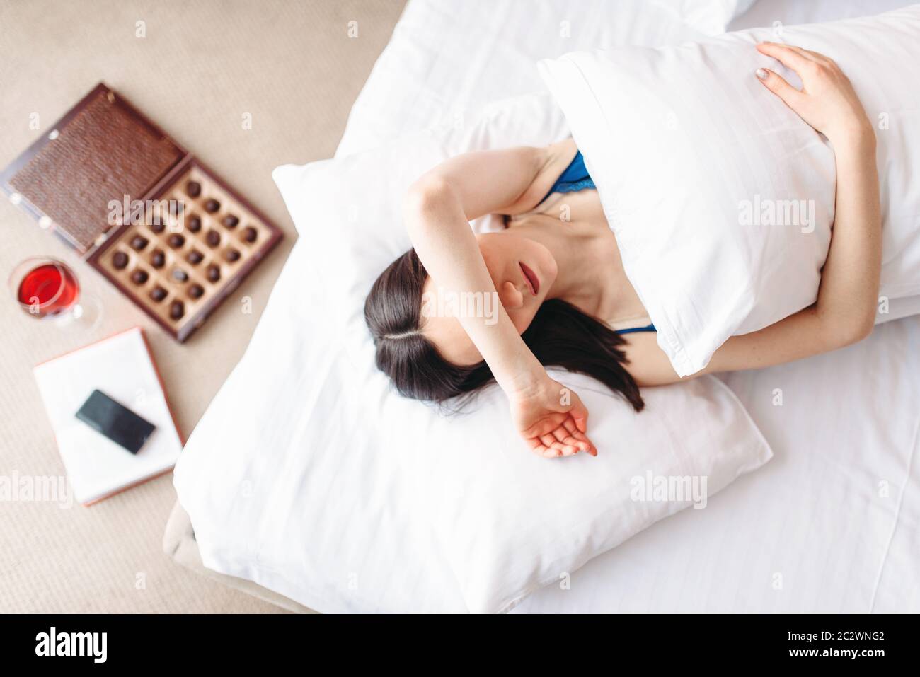 Crying Woman Lies In Bed Under The Blanket Sweet Box And Tv Remote