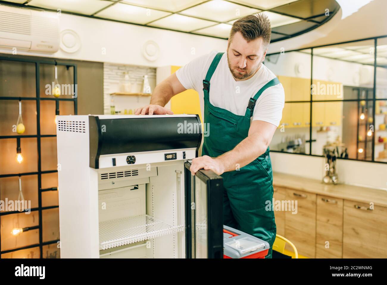 Worker with toolbox repair refrigerator at home. Repairing of fridge ...