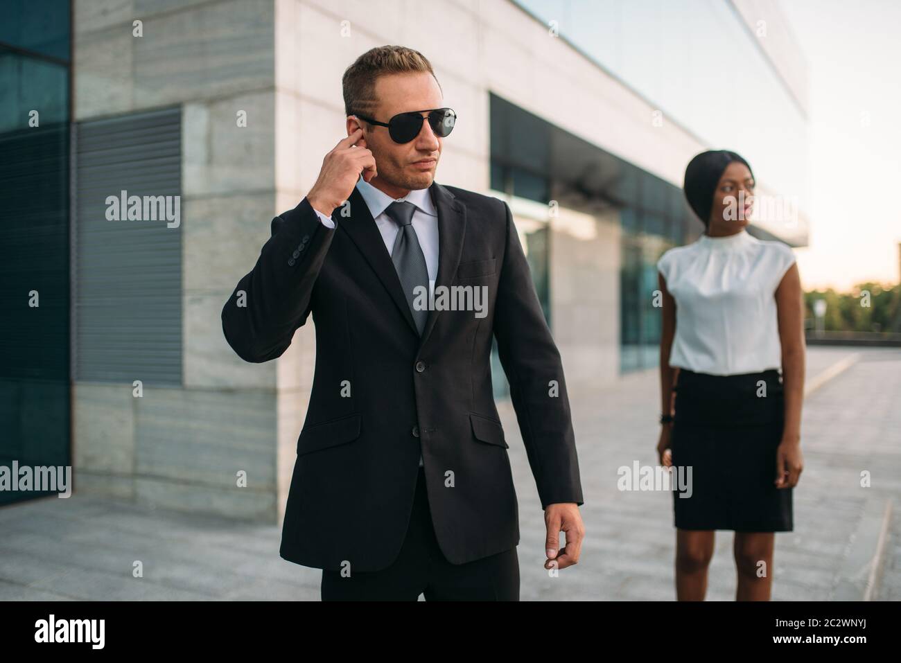 Personal bodyguard in sunglasses and black business woman. Security ...